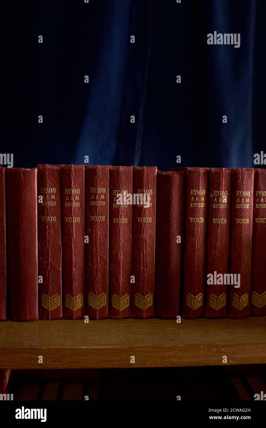 A row of old Hymn Books in a rural church with a blue curtain backdrop ...