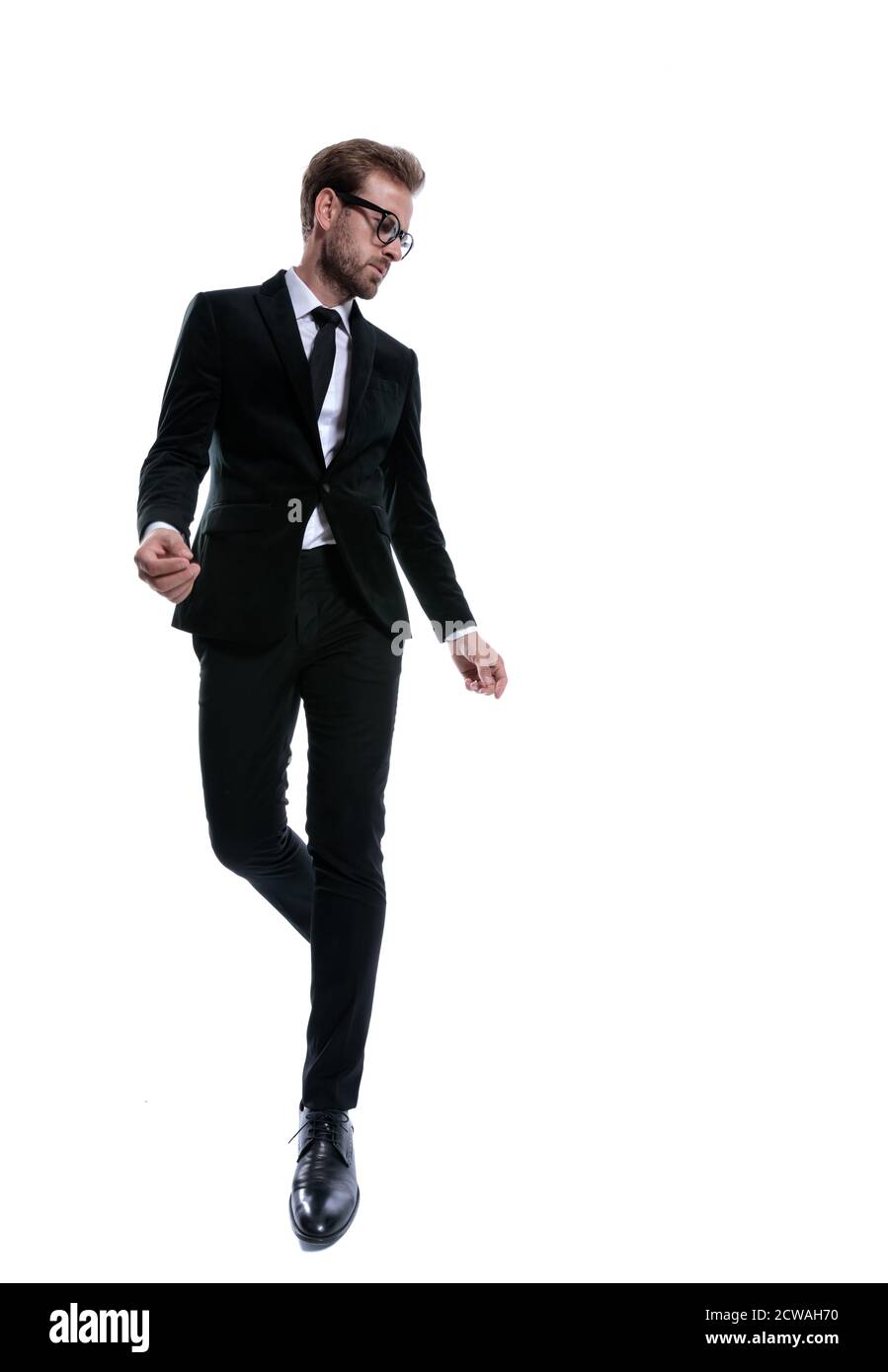 cool dramatic man in black suit looking to side, holding hands in ...