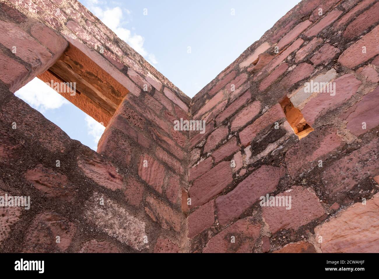 Inside a corner of a wall of an old castle made of stone with blue sky ...