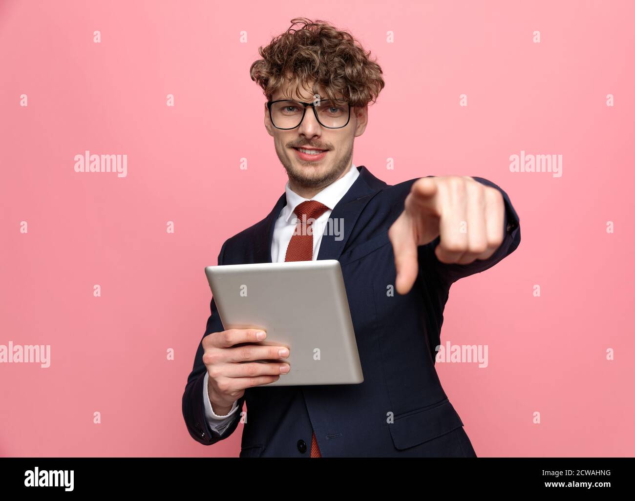elegant young businessman in navy blue suit wearing glasses holding tab ...