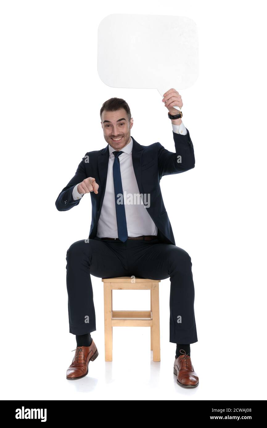 Laughing businessman pointing forward and holding speech bubble while ...