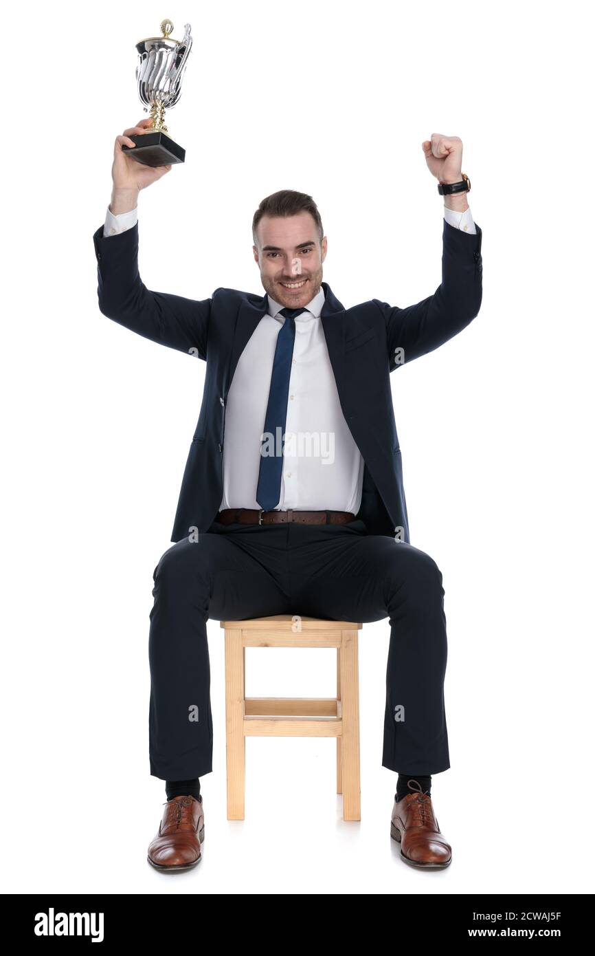Happy businessman holding trophy and celebrating with hands in the air ...