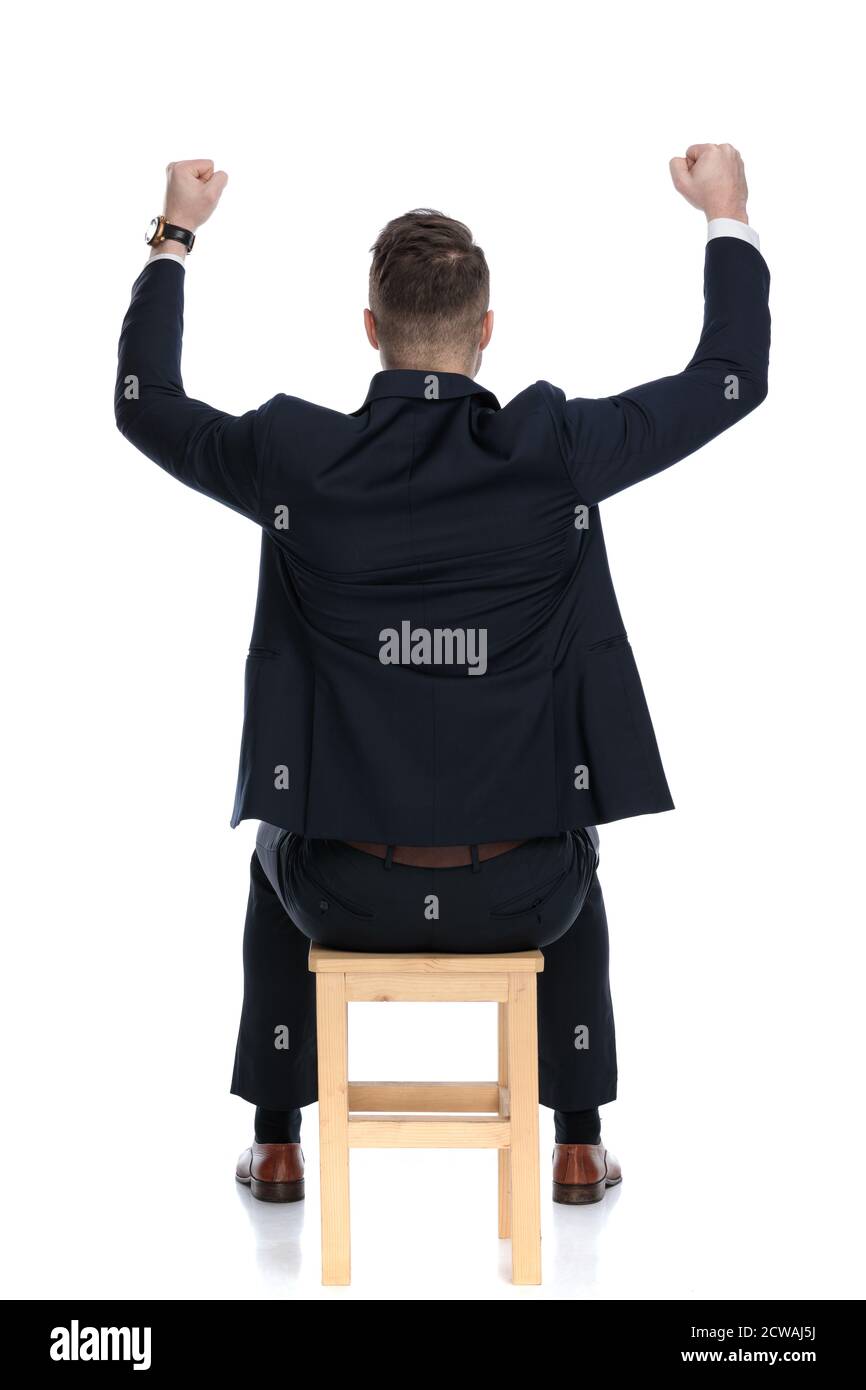 Back view of a celebrating businessman throwing his hands in the air ...