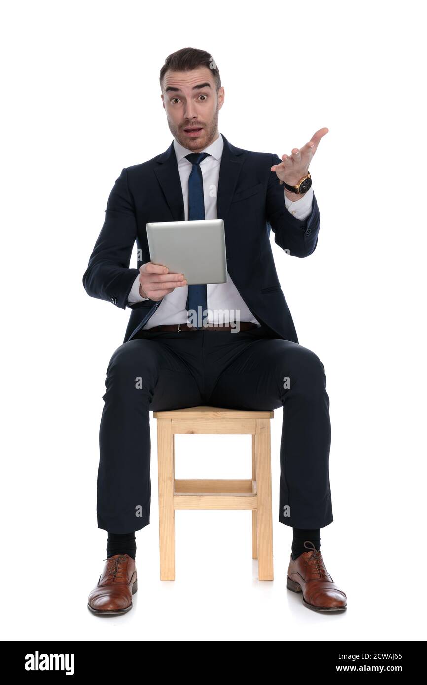Nervous businessman holding tablet and being afraid while sitting on a ...