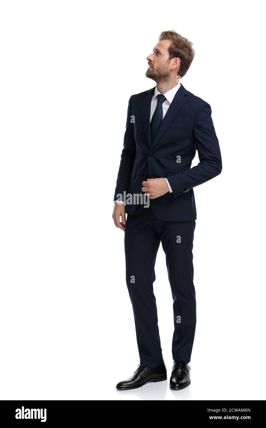 confused young man in navy blue suit looking up and standing isolated ...