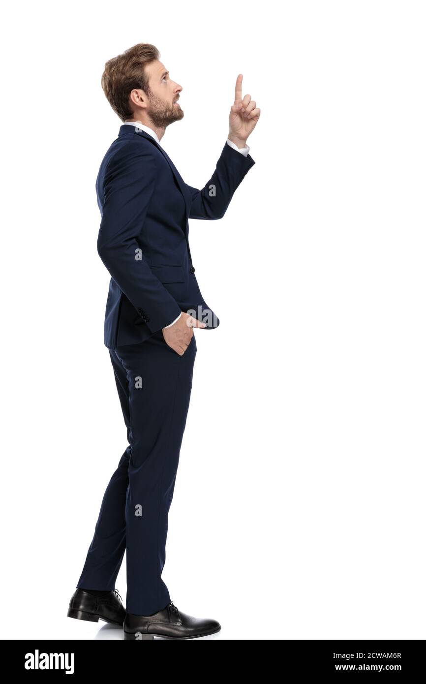 young businessman looking above head and pointing finger, walking ...