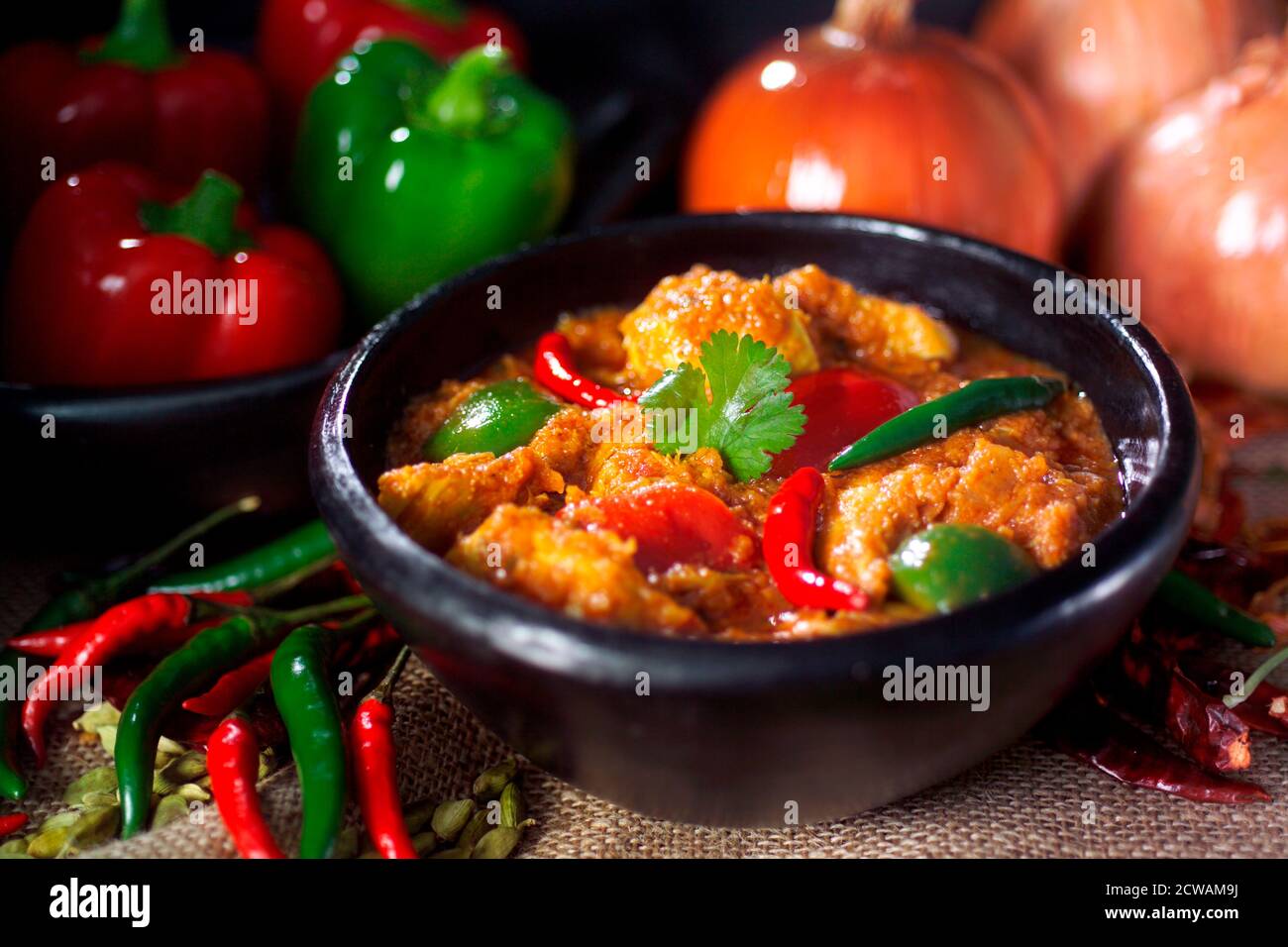 Welsh chicken curry in a rustic bowl with ingredients in the background ...