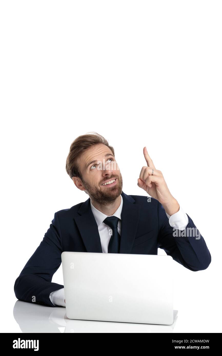 happy businessman in navy blue suit pointing finger above, smiling and ...