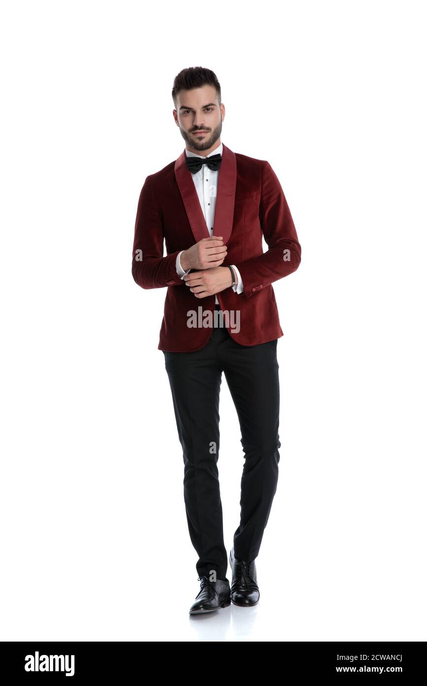 cool fashion model in red velvet tuxedo touching hands and walking ...