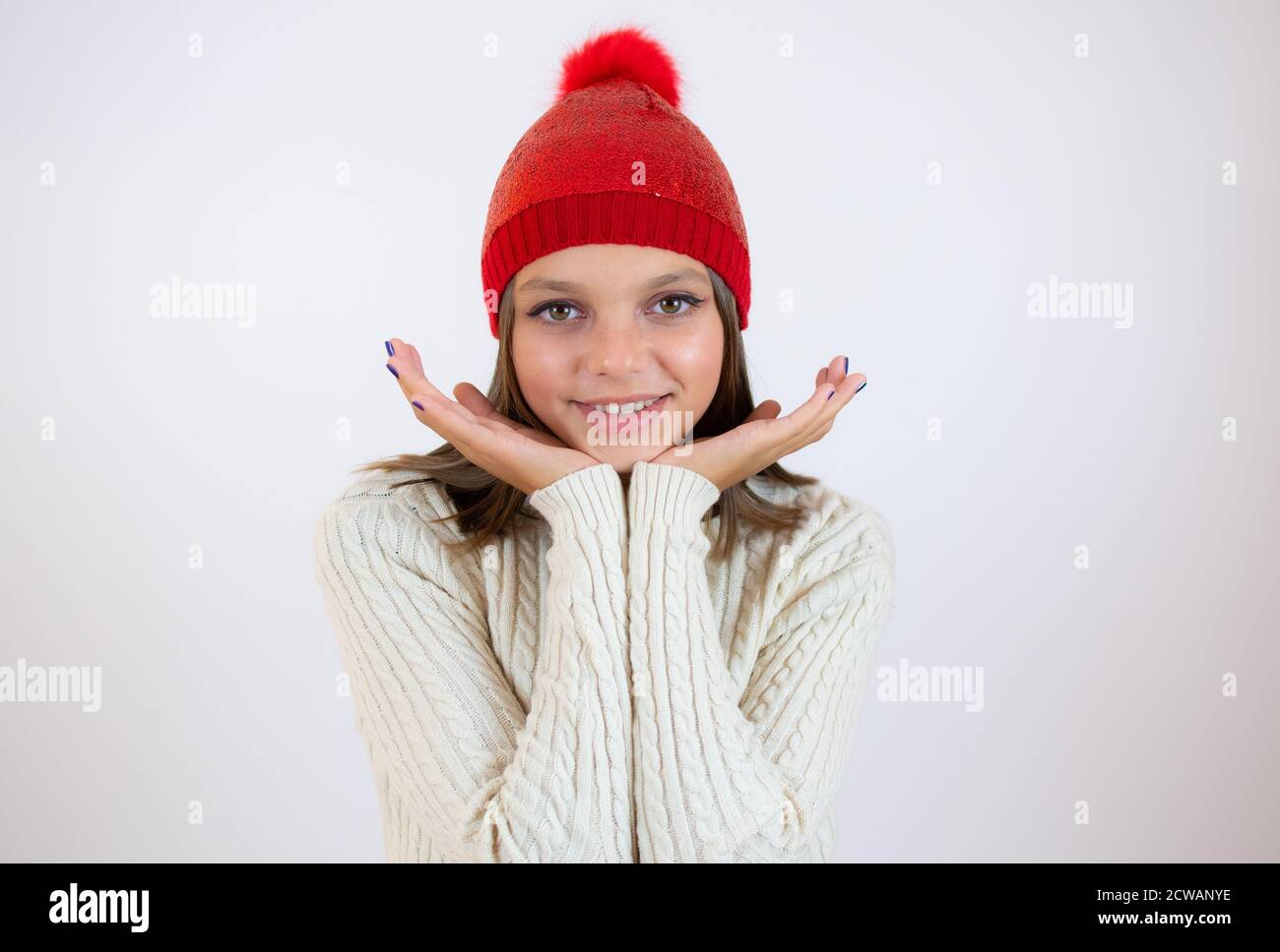 Pretty girl wearing red winter hat and sweater over white background ...
