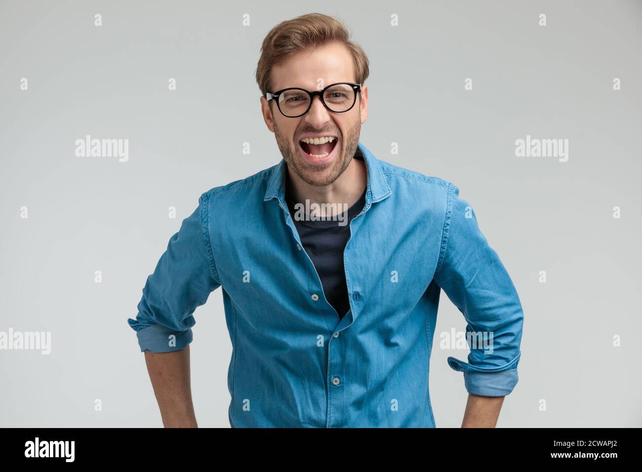happy young casual model laughing and screaming of joy on grey ...