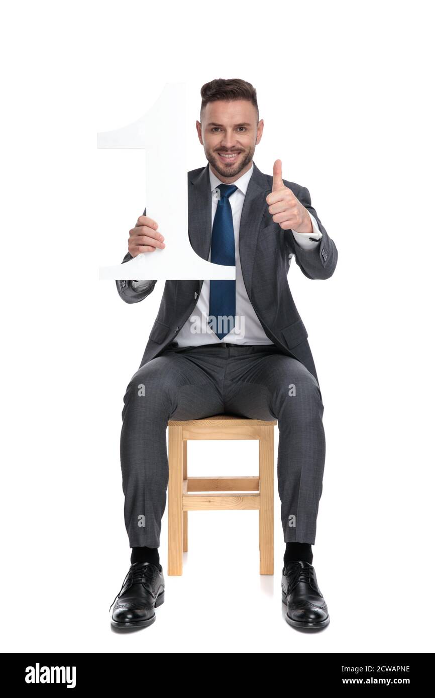 happy young businessman holding number one sign and making thumbs up ...