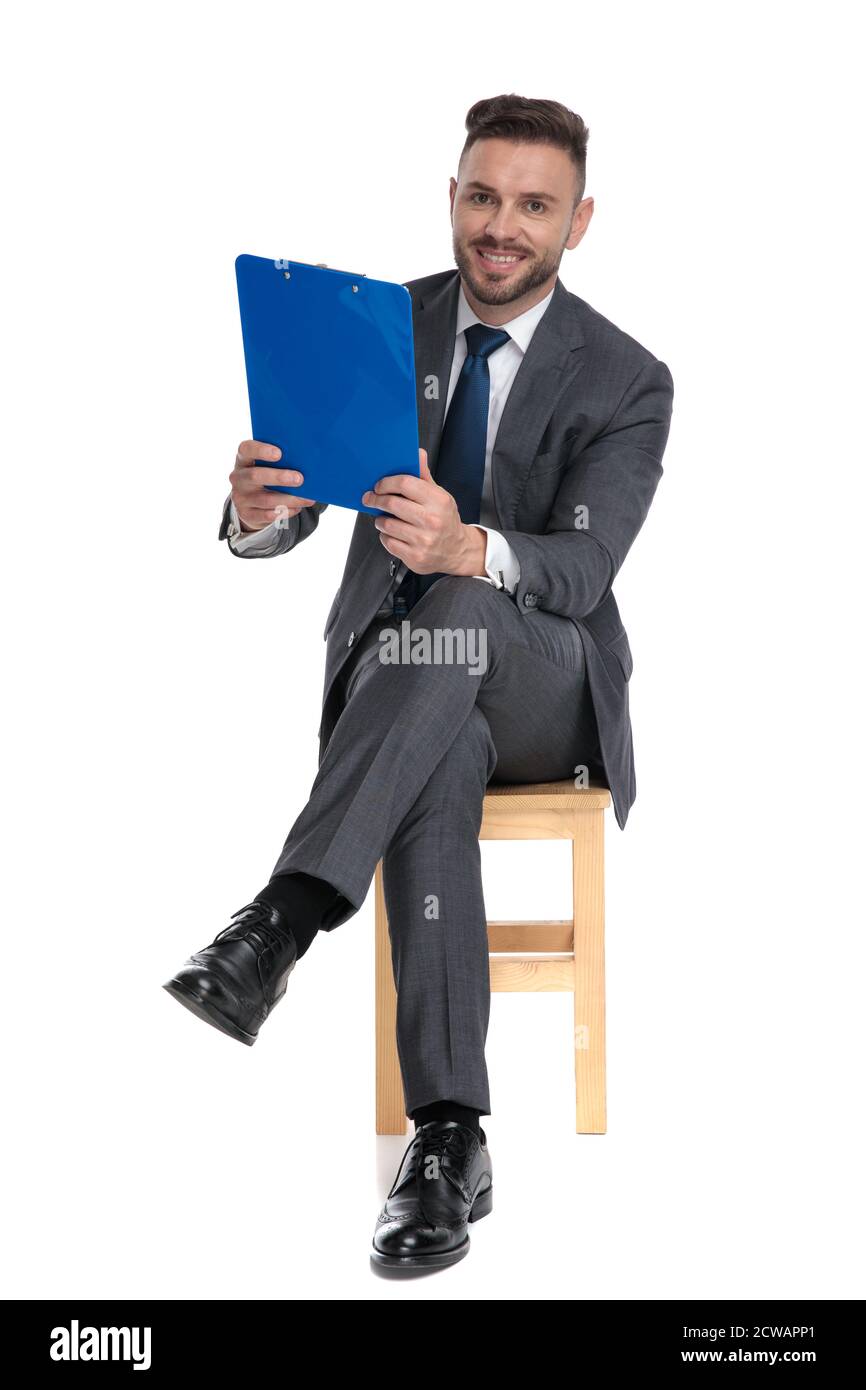 happy young man holding clipboard and smiling, sitting isolated on ...