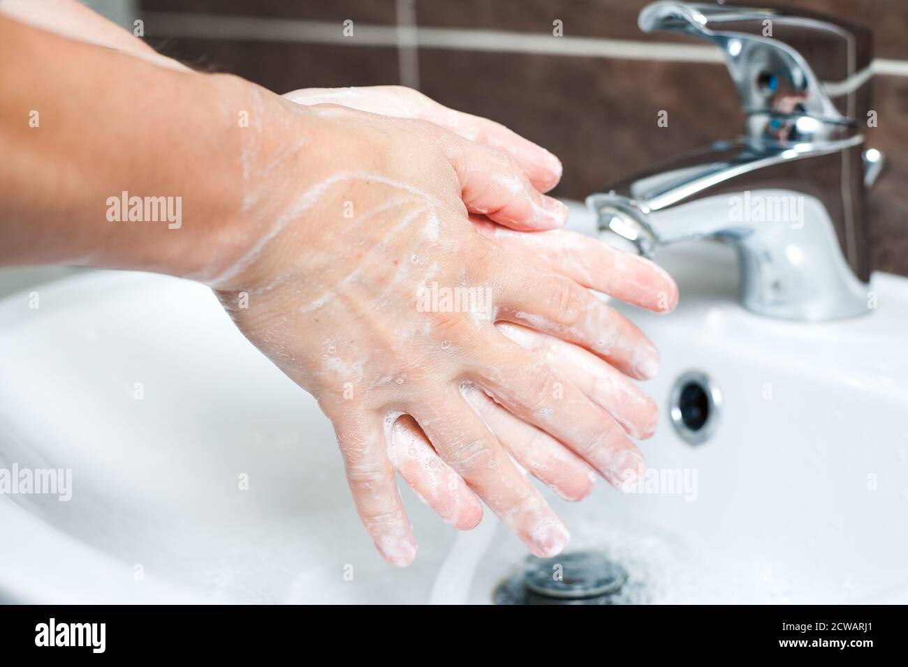 Hygiene concept. Washing hands with soap under the faucet with water ...
