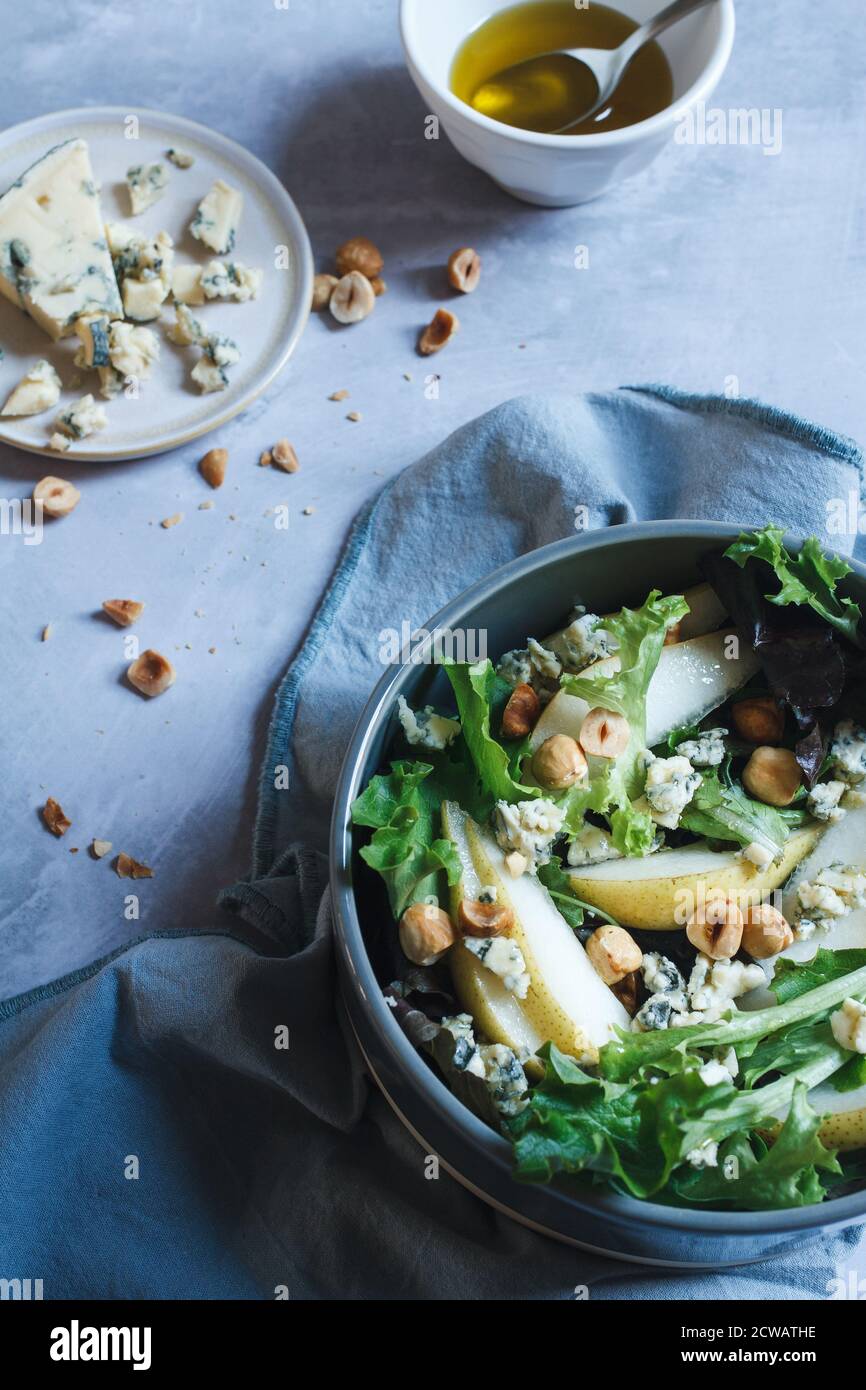 Autumn salad in a dark grey bowl. Mixed leaves with pear slices, blue ...