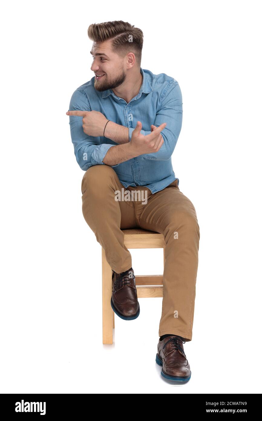 smiling casual man in denim shirt looking to side and pointing finger ...