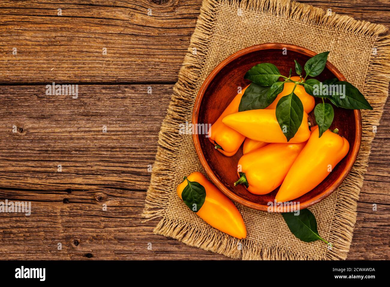 Ripe whole yellow mini peppers in clay bowl. Fresh harvest, traditional ...