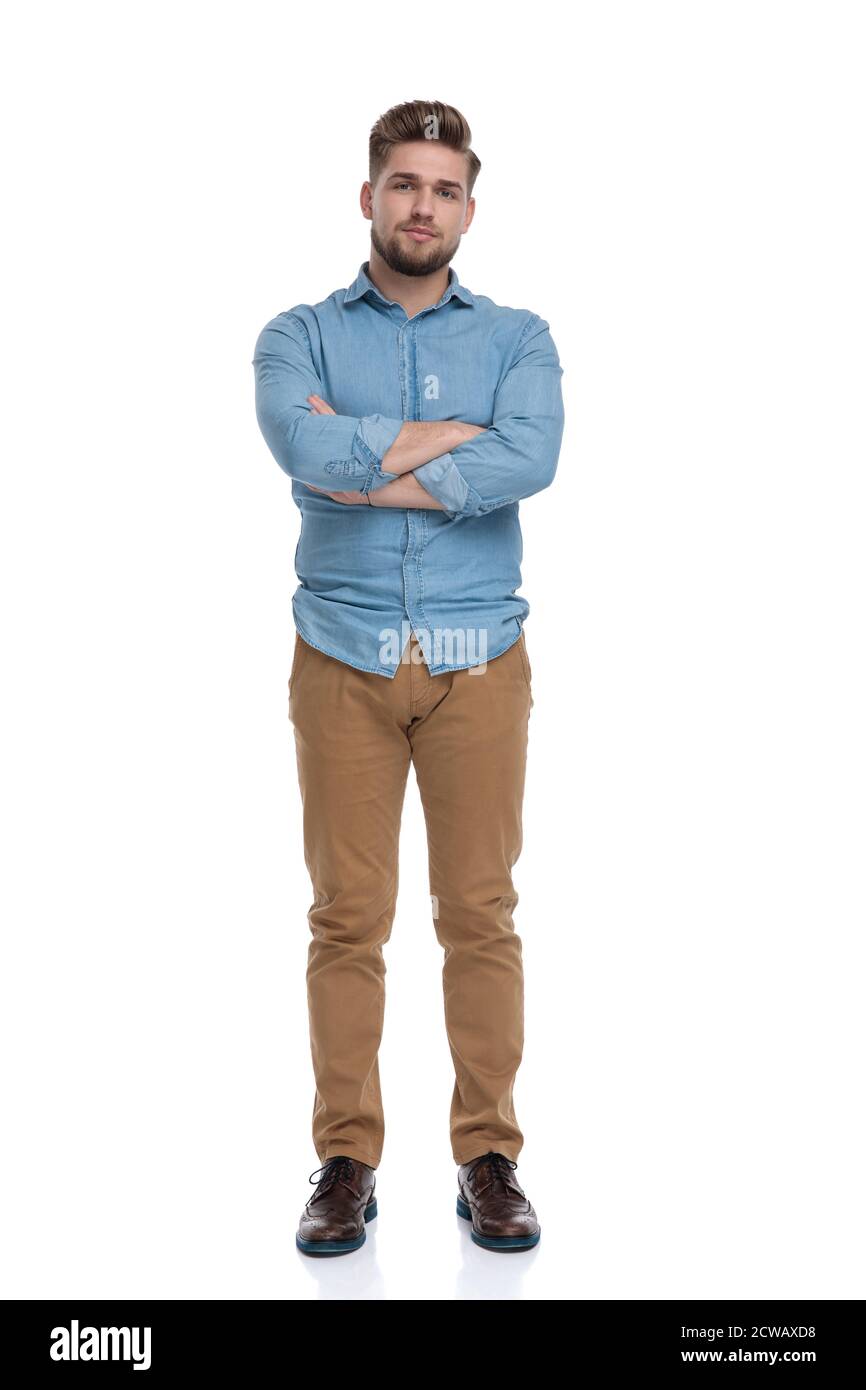 Serious casual man holding his hands folded at his chest while standing ...