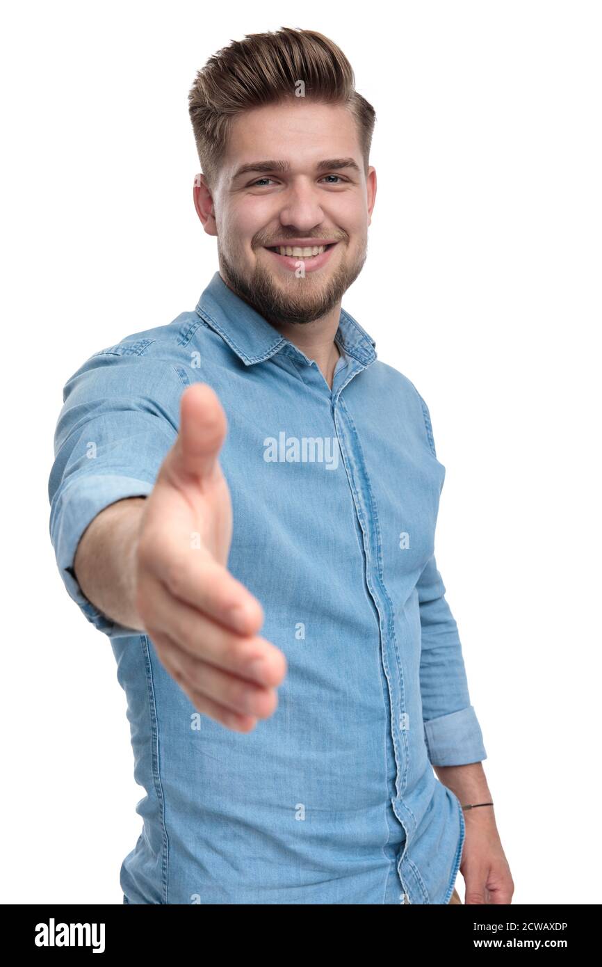Positive casual man smiling and reaching for a handshake, standing on ...