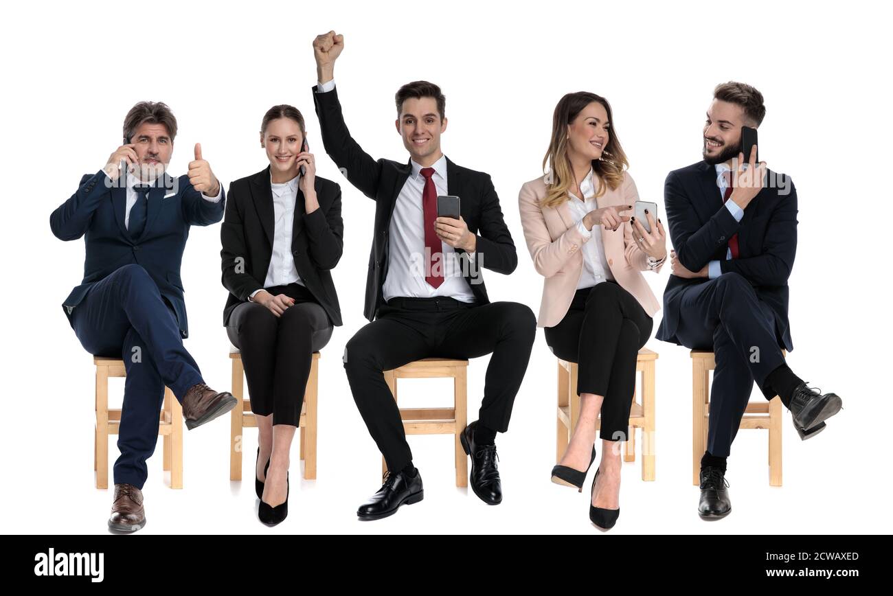 Team of 5 businessmen celebrating and holding their phones while ...