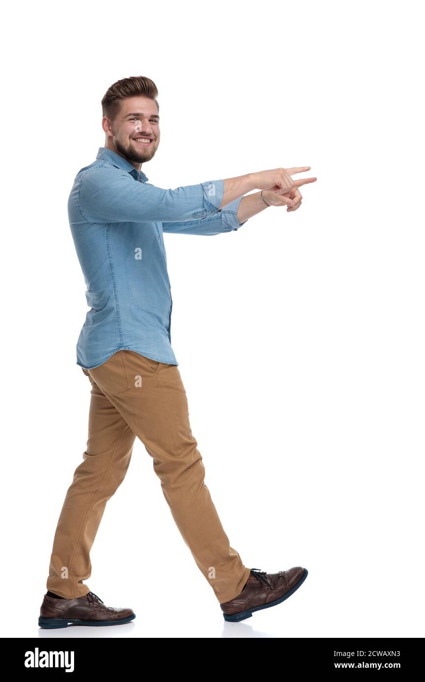 Side view of a cheerful casual man pointing forward with both hands ...