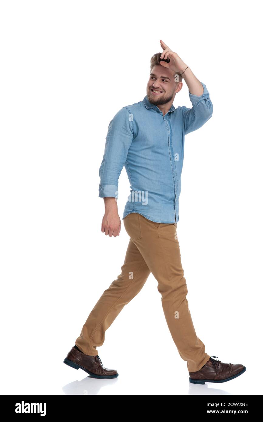Side view of a positive casual man saluting while stepping on white ...