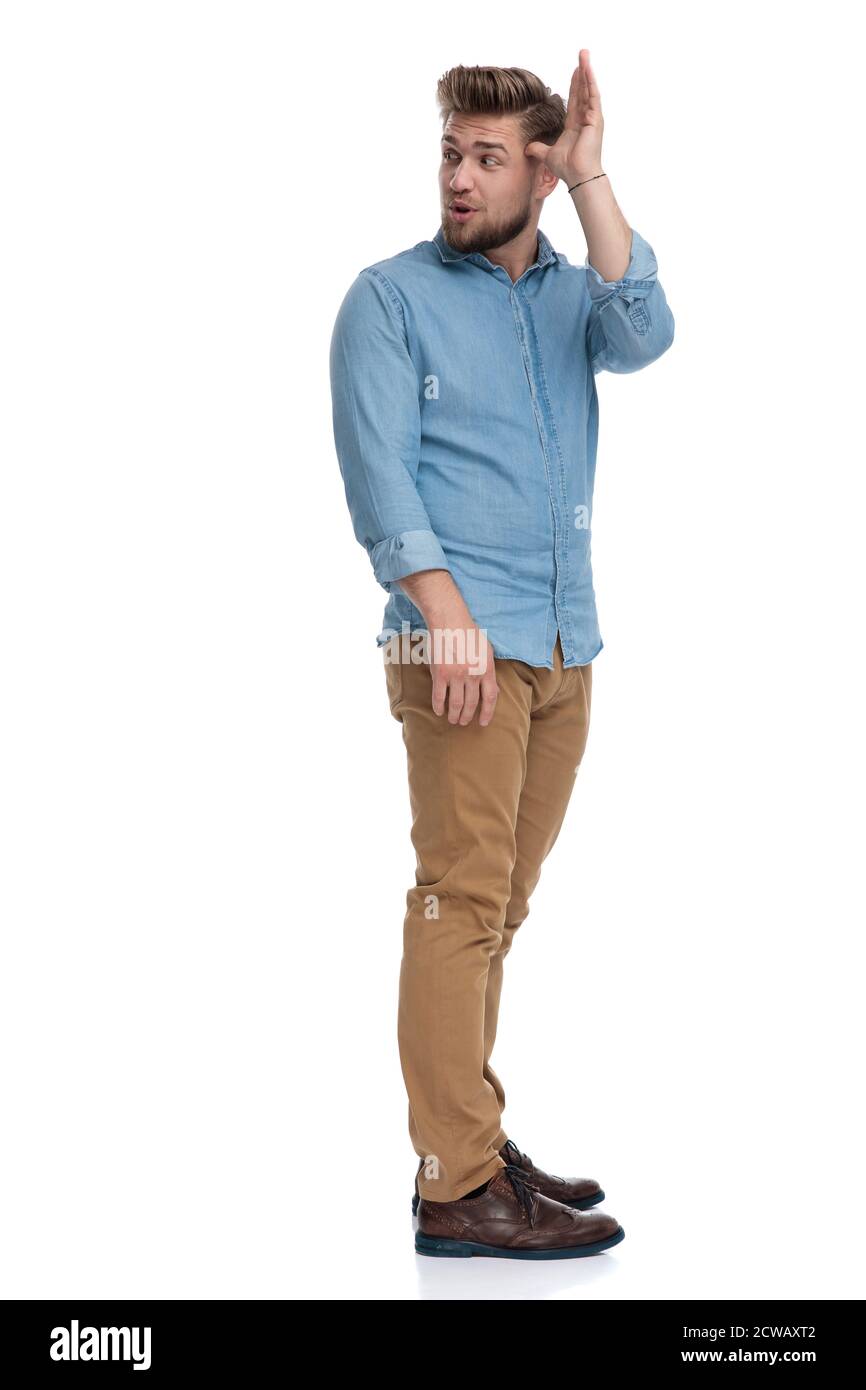 Side view of a young casual man making a funny face and gesture ...