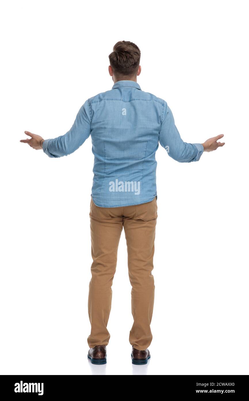Rear view of a young casual man welcoming and standing on white studio ...