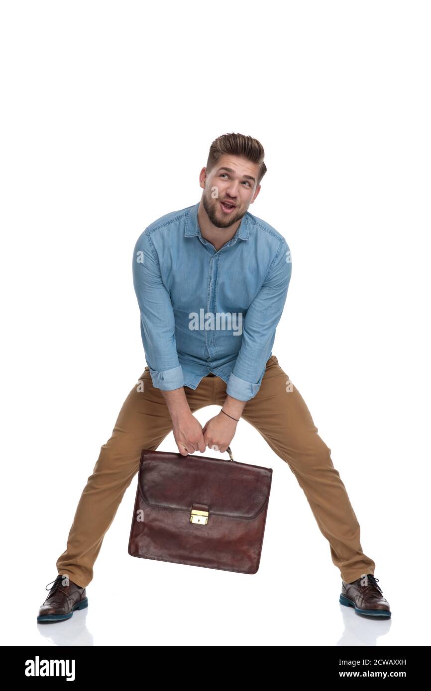 Young casual man making a funny pose while holding briefcase and ...