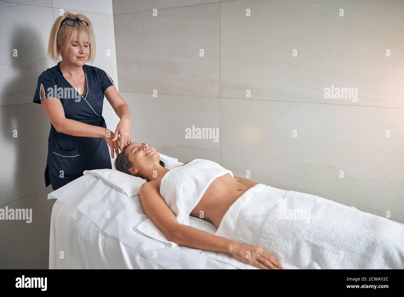 Charming masseur massaging woman head in spa salon Stock Photo - Alamy