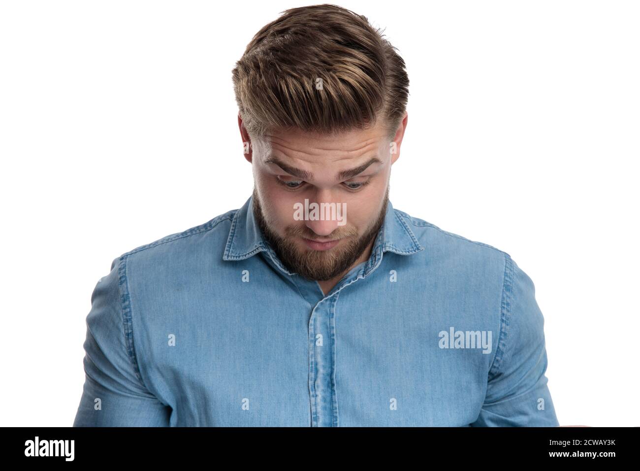 Shocked casual man looking down, standing on white studio background ...