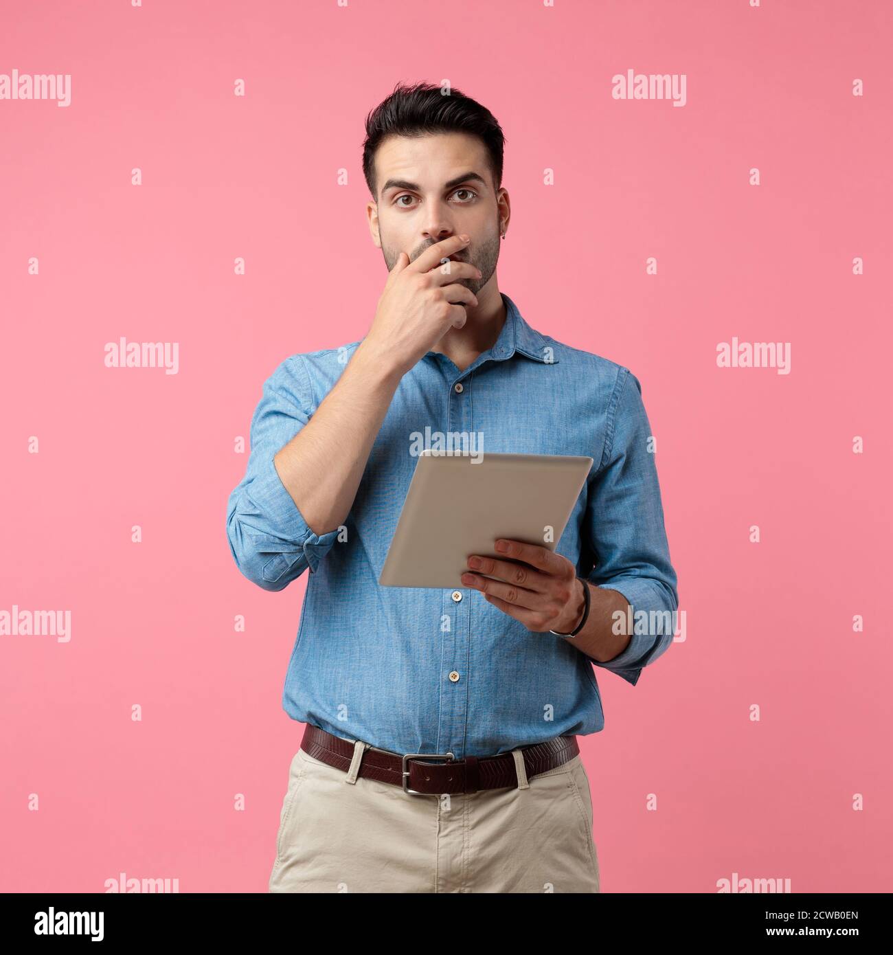 shocked casual guy holding tab and covering mouth with hand, standing ...