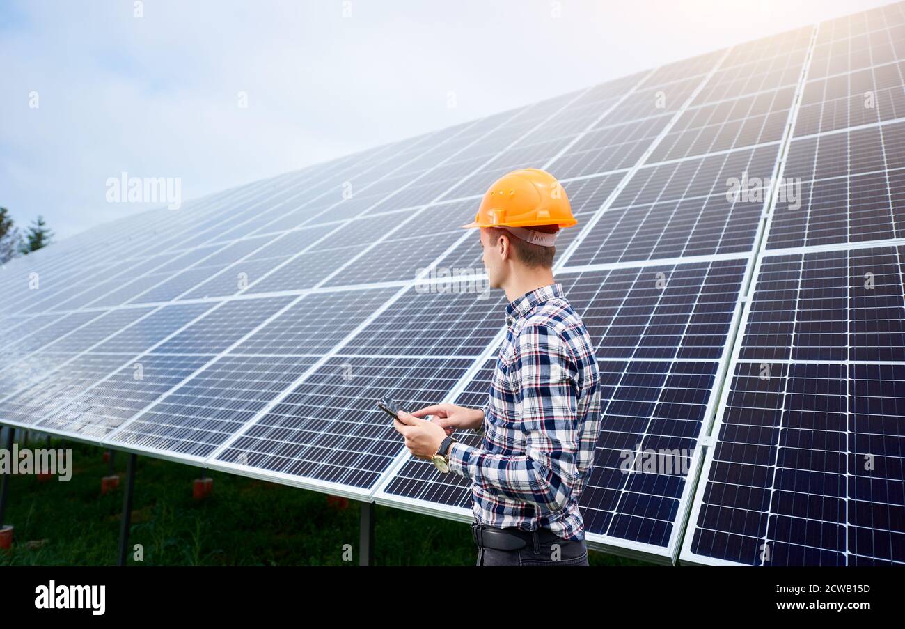 Engineer in helmet with tablet in hands standing near solar panels on ...