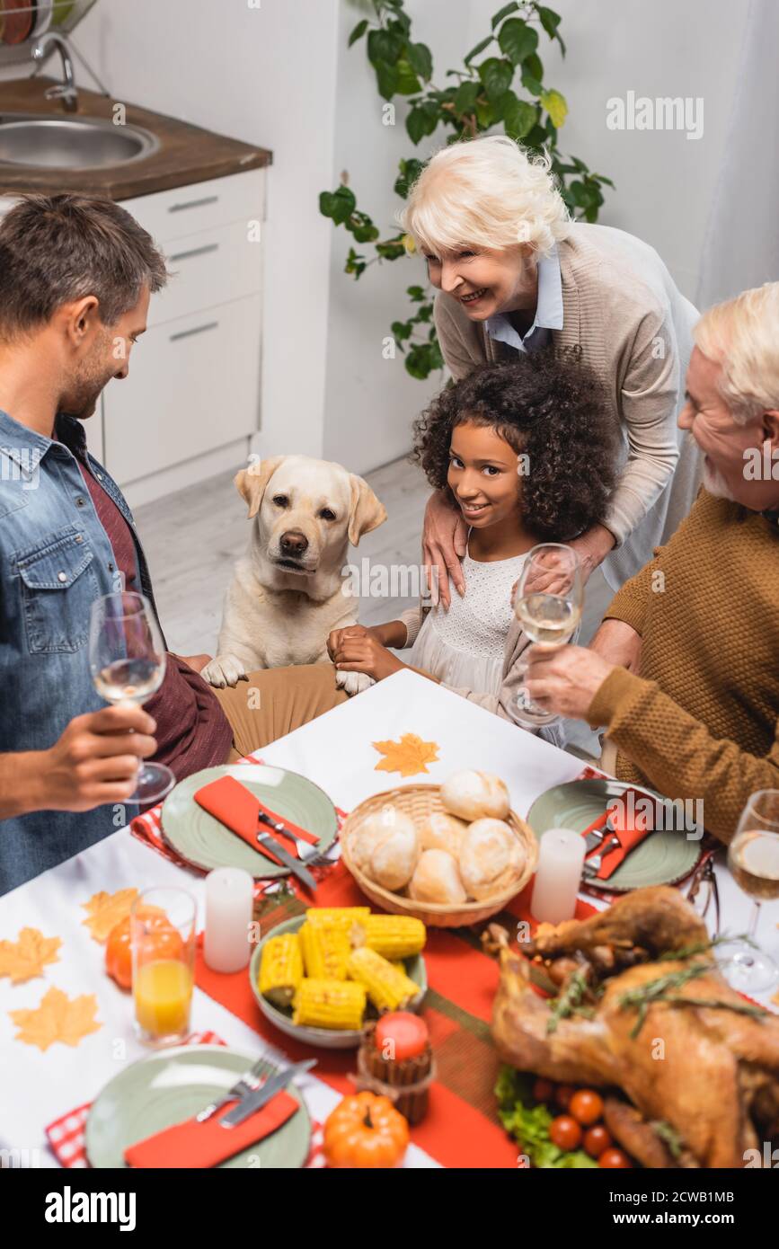 multicultural family and golden retriever near table served with ...