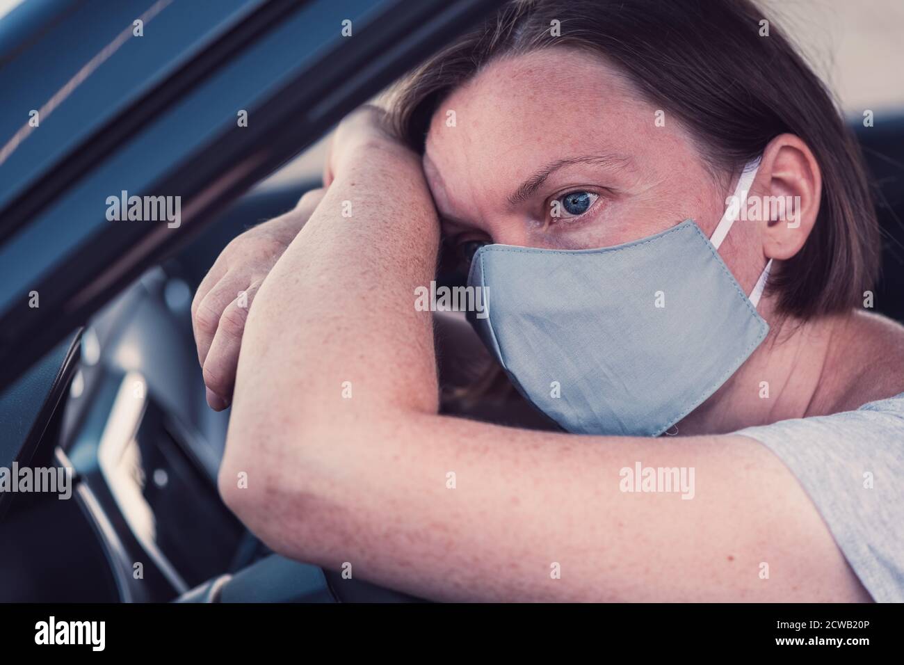 Bored woman with protective face mask waiting in the car in new normal ...