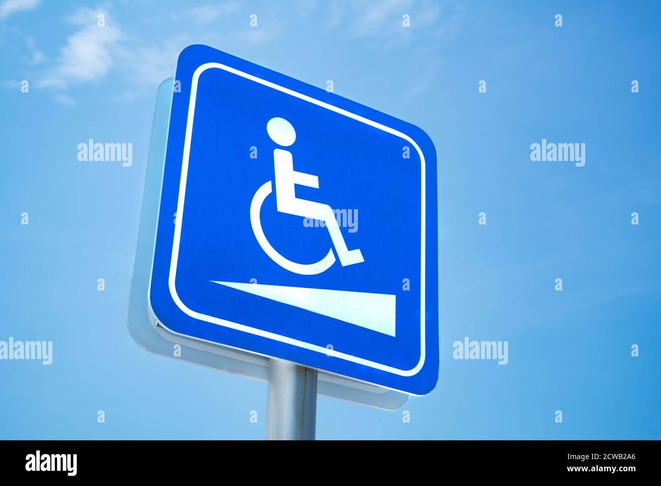 Handicap sign. White symbol over blue background on blue sky background ...