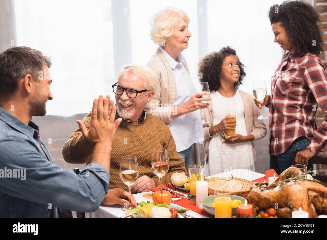 joyful men giving high five during thanksgiving dinner with ...