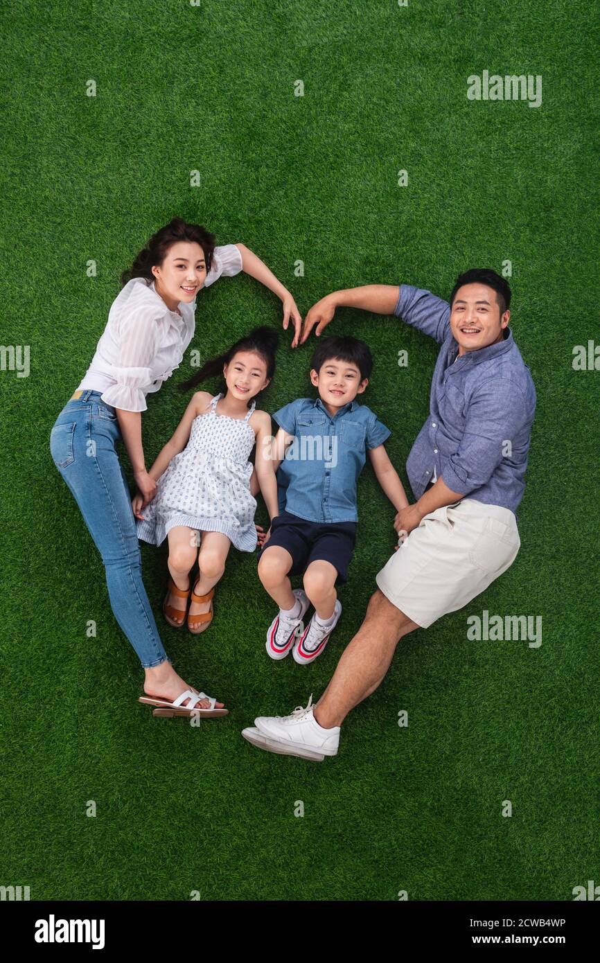 Happiness of a family of four heart lay on the grass Stock Photo - Alamy