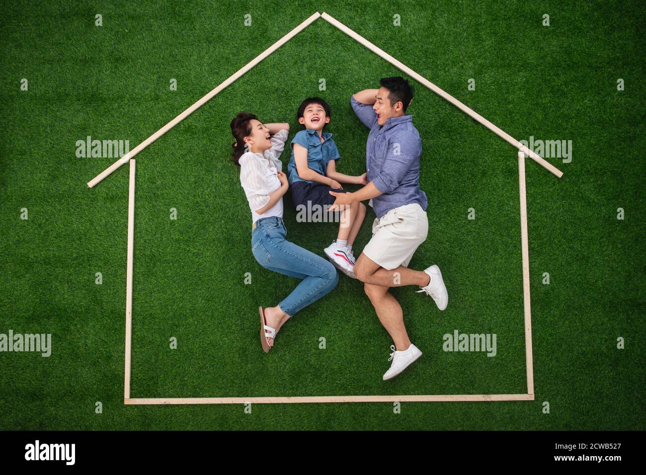 Happy three lay on the grass playing in the house outline Stock Photo ...