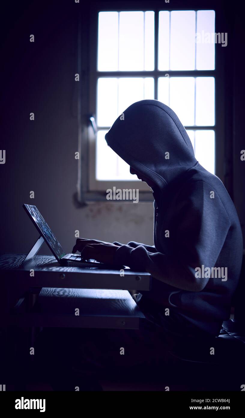 Computer hacker with hoodie behind his computer Stock Photo - Alamy