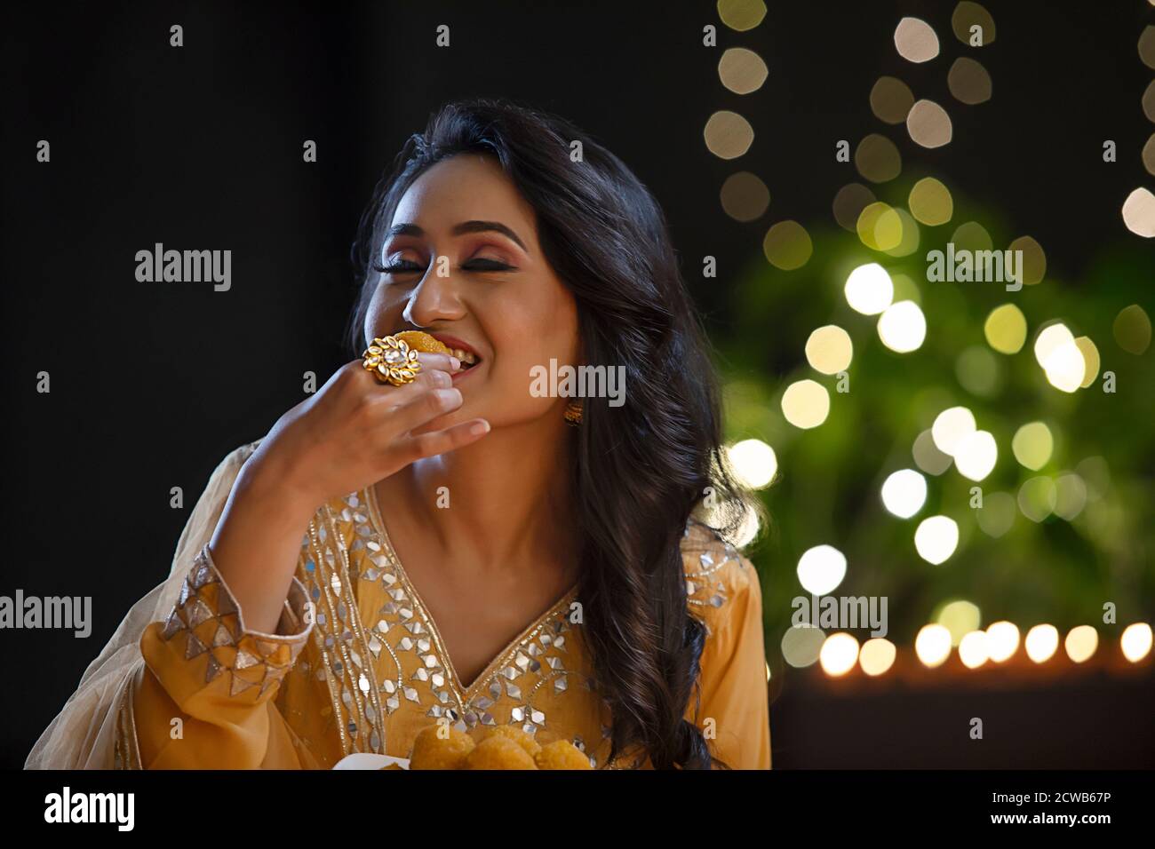Woman eating a ladoo with a smile on her face Stock Photo - Alamy