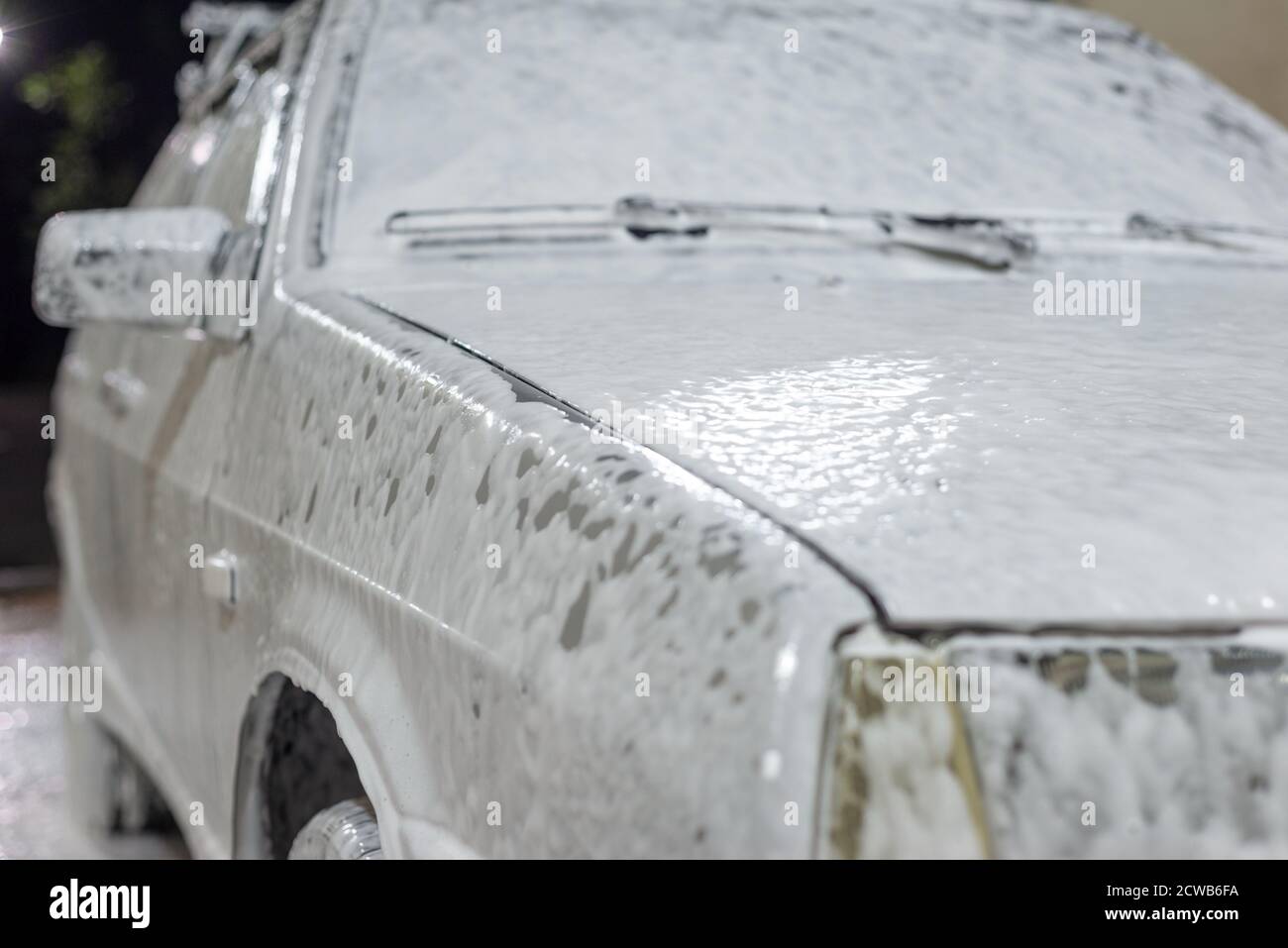 car in foam at the car wash. Dirty car after treatment with soapy water ...