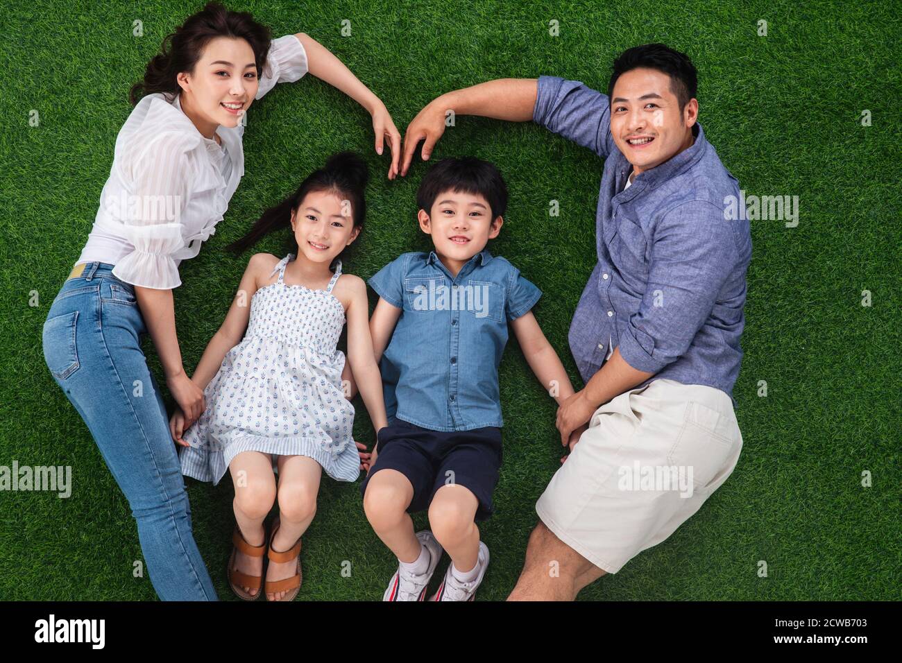 Happiness of a family of four heart lay on the grass Stock Photo - Alamy