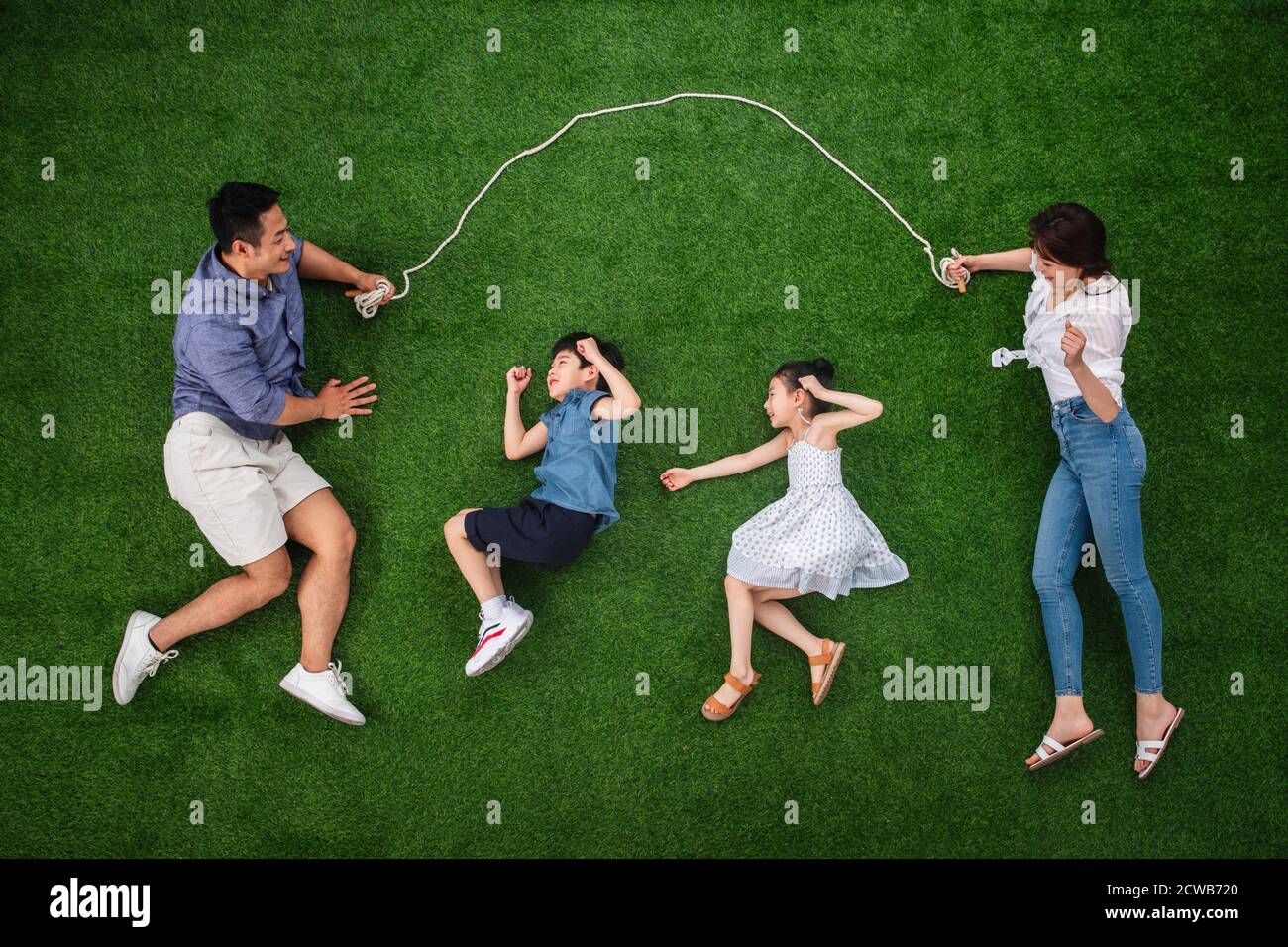 The happy family of four rope jumping on the grass Stock Photo - Alamy