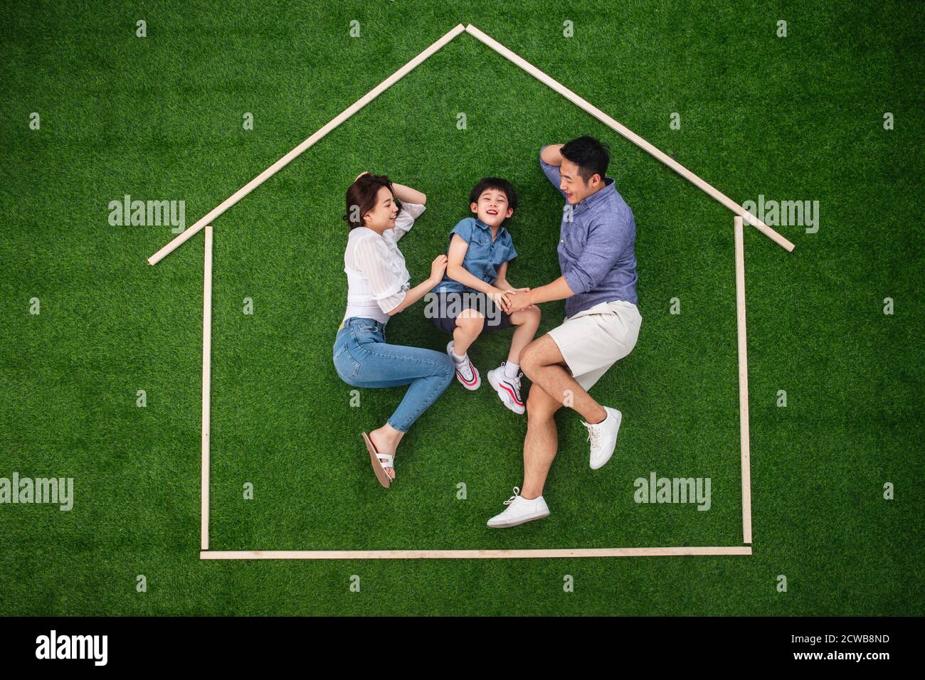 Happy three lay on the grass playing in the house outline Stock Photo ...