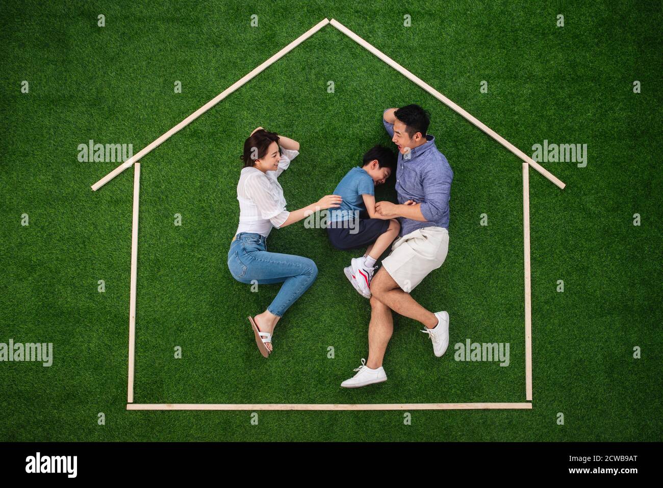 Happy three lay on the grass playing in the house outline Stock Photo ...