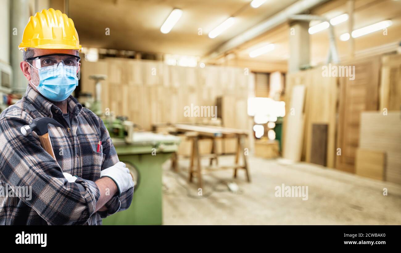 Carpenter worker in the carpentry workshop, wears helmet, goggles ...