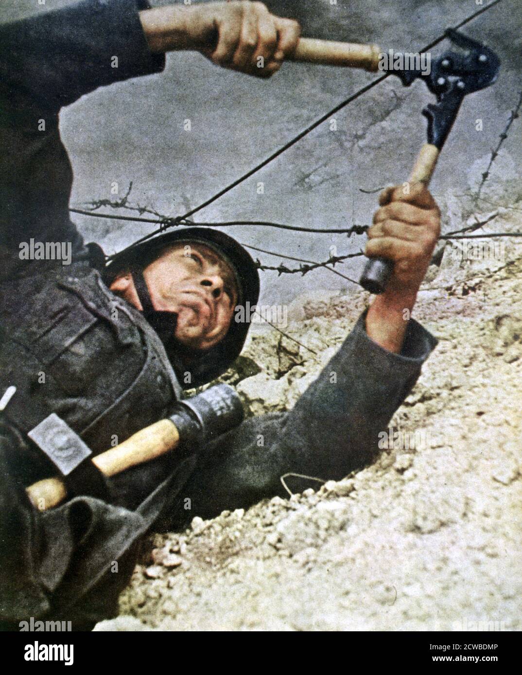A German soldier cutting through barbedwire during an assault, 1942. A ...