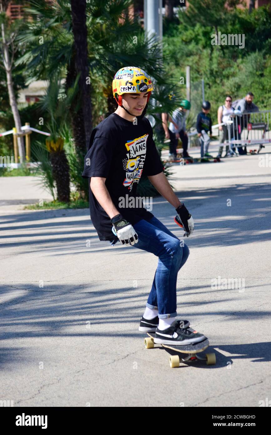 A boy wearing a helmet is riding his longboard on a city street Stock ...