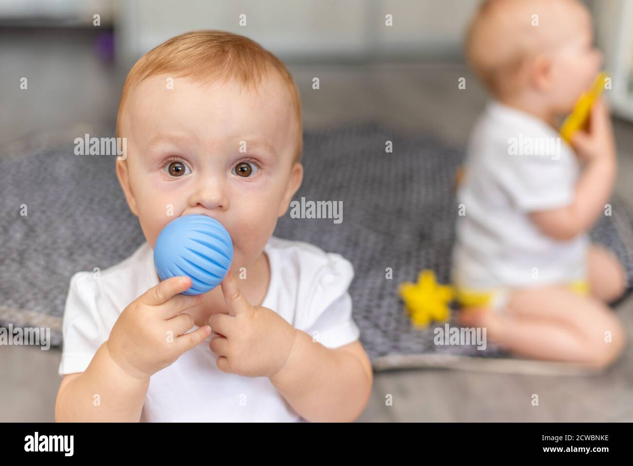 Cute happy babies play together on the floor with toys and take them in ...